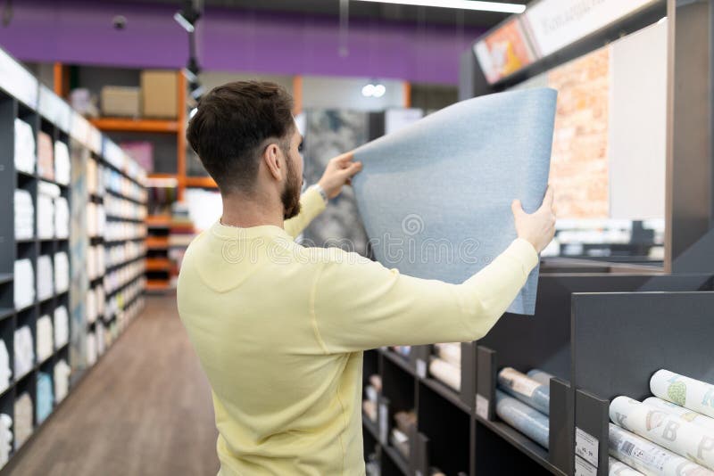 A Man Chooses Wallpaper for Pasting Walls in a Hardware Store Stock ...