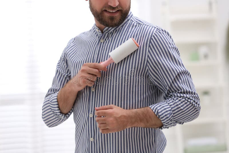 Man Cleaning Clothes with Lint Roller at Home, Closeup Stock Image ...