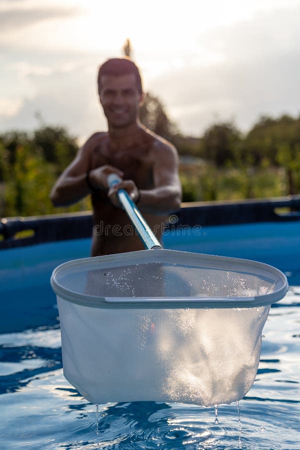 Man cleaning pool with net stock photo. Image of tool - 256069602