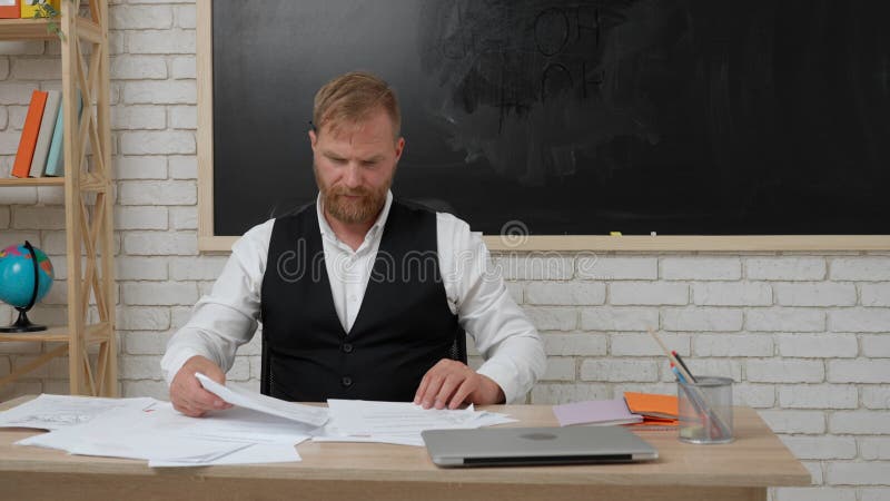 Man College Teacher Sit at Desk in Classroom, Grading Tests Homework ...