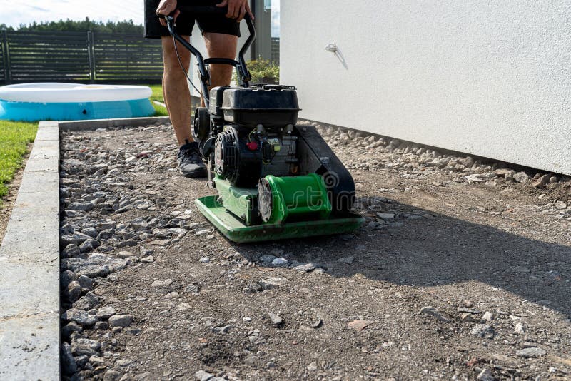 A Man Compacts Rubble on a Terrace Under Construction Using a Hand-held ...