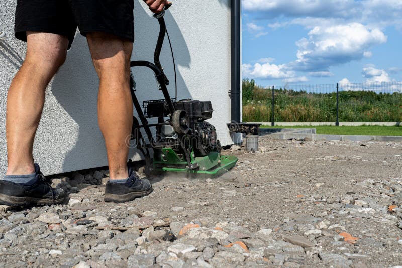 A Man Compacts Rubble on a Terrace Under Construction Using a Hand-held ...