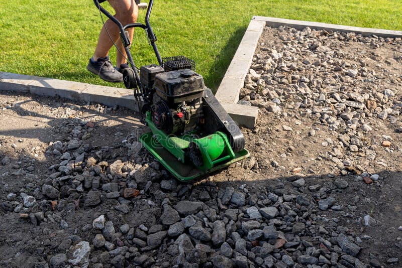 A Man Compacts Rubble on a Terrace Under Construction Using a Hand-held ...