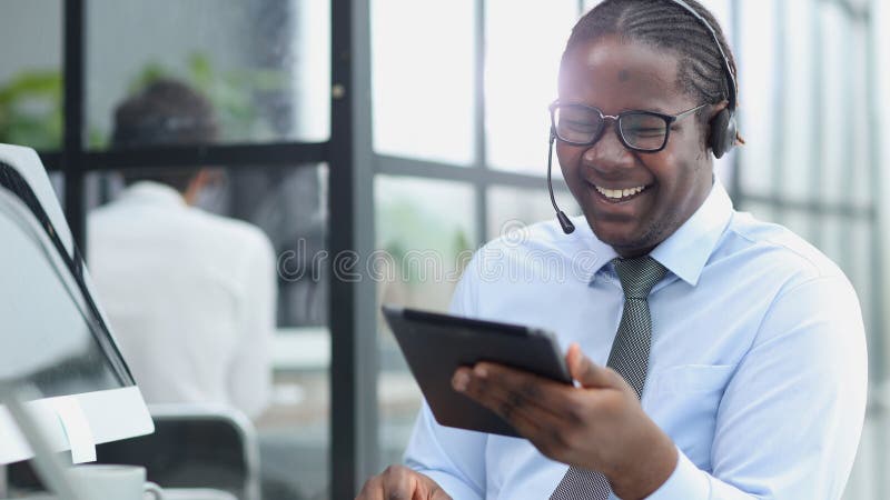 A Man at a Computer in a Call Center Talking Using Headphones with a ...