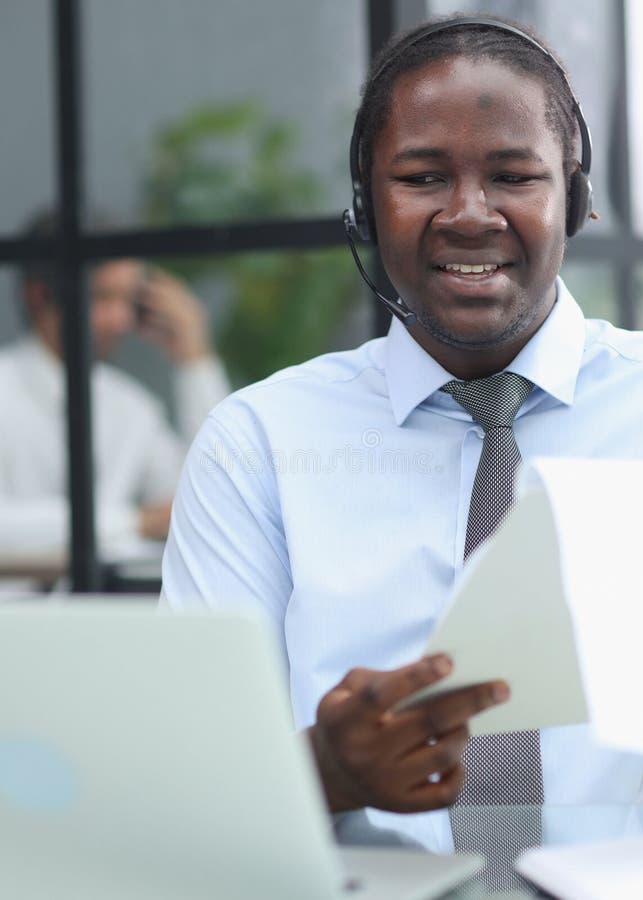 A Man at a Computer in a Call Center Talking Using Headphones with a ...