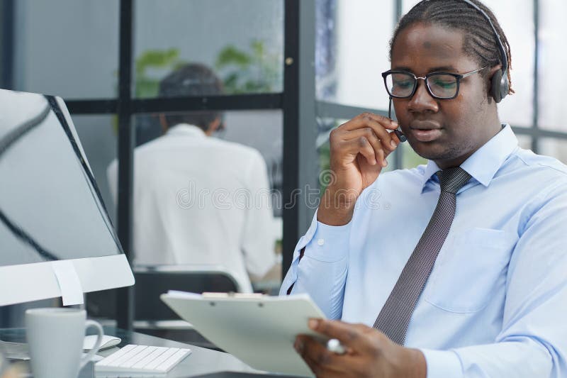 A Man at a Computer in a Call Center Talking Using Headphones with a ...