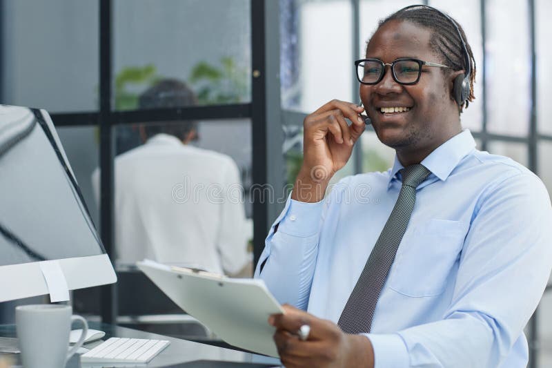A Man at a Computer in a Call Center Talking Using Headphones with a ...