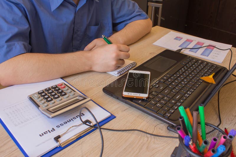 The Man and Computer are Using a Calculator on the Table in the Office ...