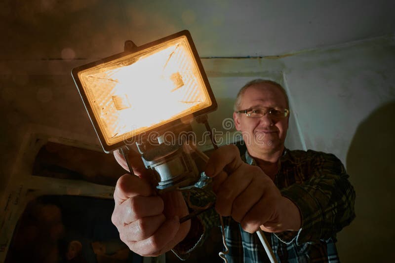 A Man at a Construction Site Demonstrates a Lantern that he Uses To ...