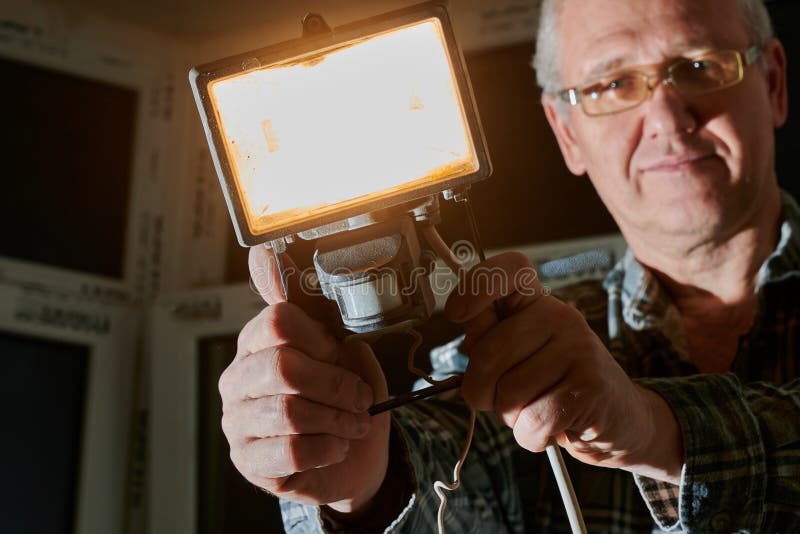 A Man at a Construction Site Demonstrates a Lantern that he Uses To ...