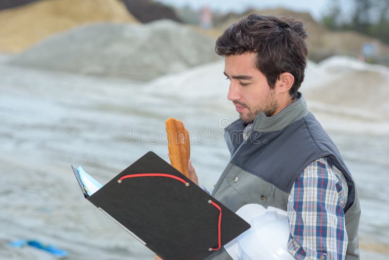 Man on Construction Site Holding File and Baguette Stock Image - Image ...