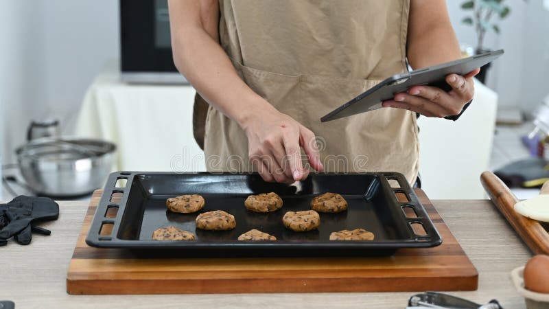A Man is Cooking in a Kitchen while Holding a Tablet. he is Using the ...