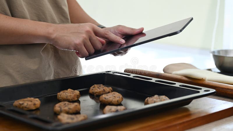 A Man is Cooking in a Kitchen while Holding a Tablet. he is Using the ...