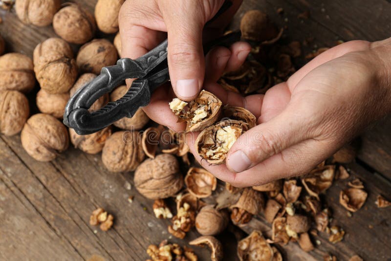 Man Cracking Walnuts at Wooden Table, Closeup Stock Photo - Image of ...