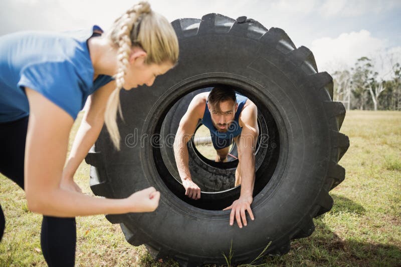 Man Crawling through the Tire during Obstacle Course while Trainer ...