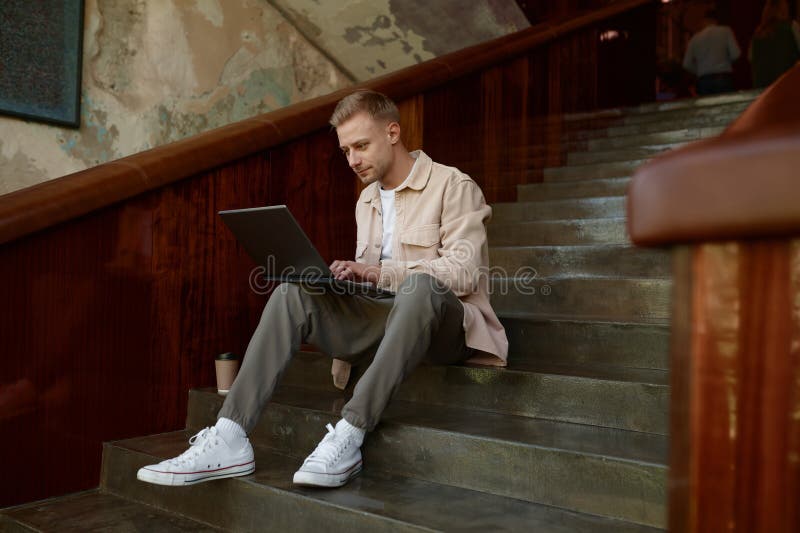 Man Working on Wireless Laptop Computer Sitting on Stairs in Office ...