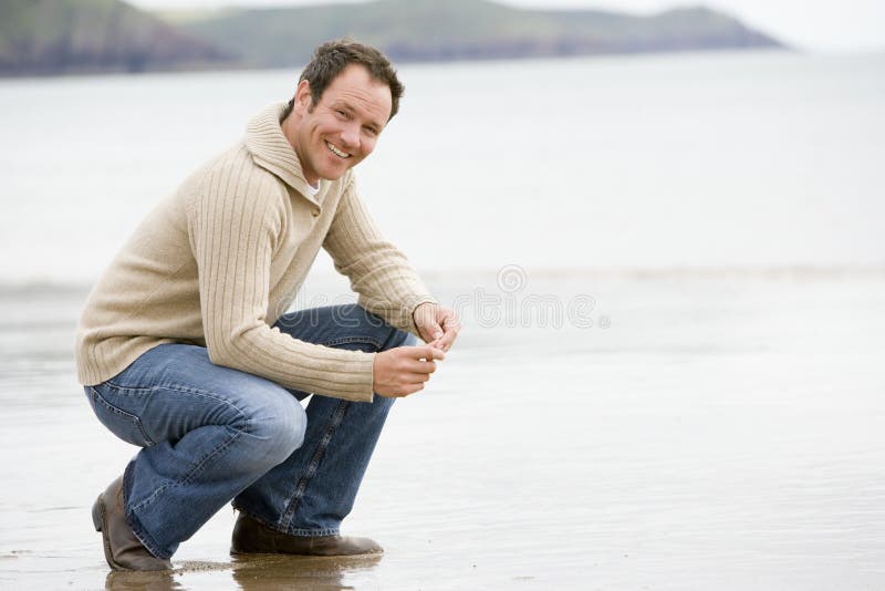 Man crouching on beach stock image. Image of autumn, contemplating ...