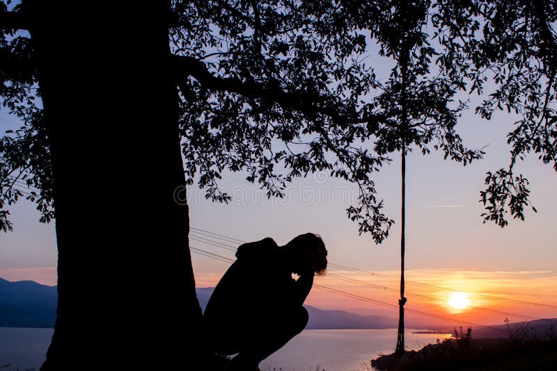 Man Crouching Under the Tree and Silhouette of the Tree. Sad Mood Stock ...
