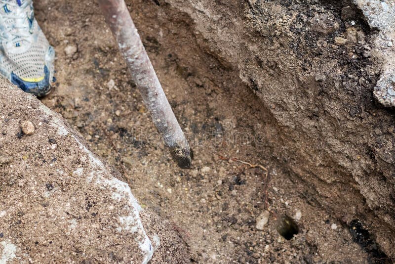 Man with a Crowbar Crushes Hard Soil while Digging a Ditch on a ...