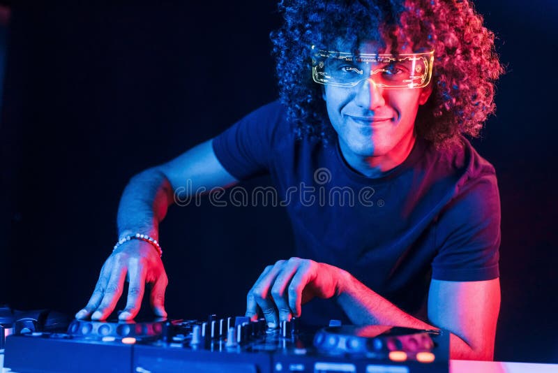 Man with Curly Hair Using DJ Equipment and Standing in the Dark Neon ...