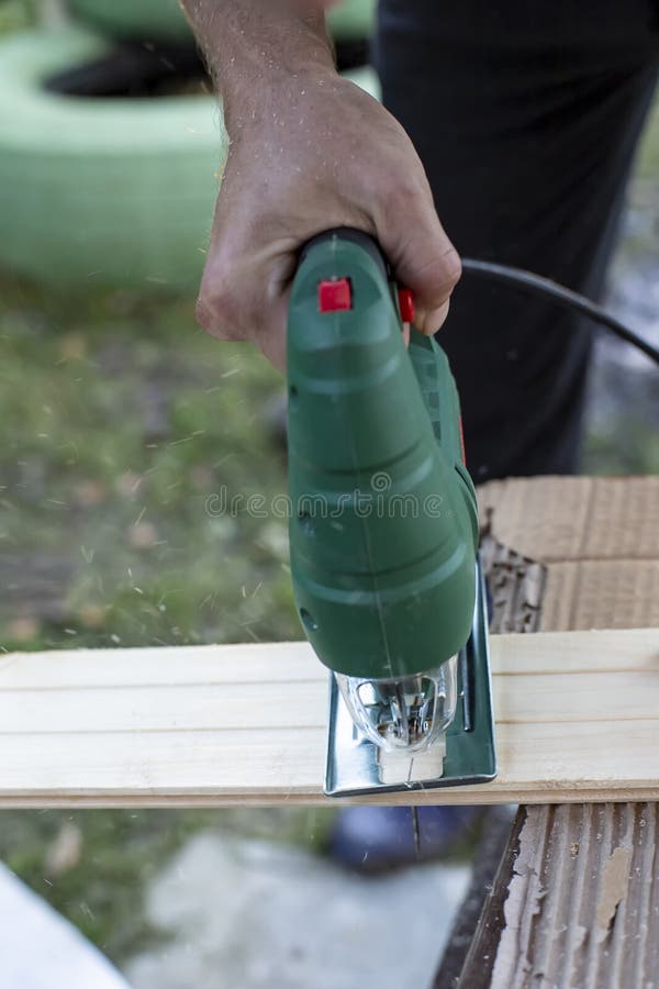 Man Cuts Wood Products, Using Electric Jigsaws Outdoors Stock Photo ...