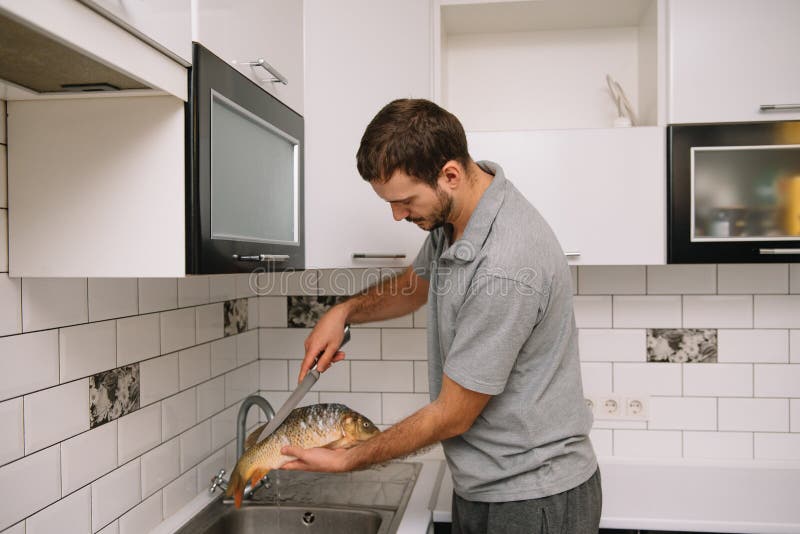 Man Cutting Fresh Fish in Kitchen in Home. Man Butchering Fish for Cook ...