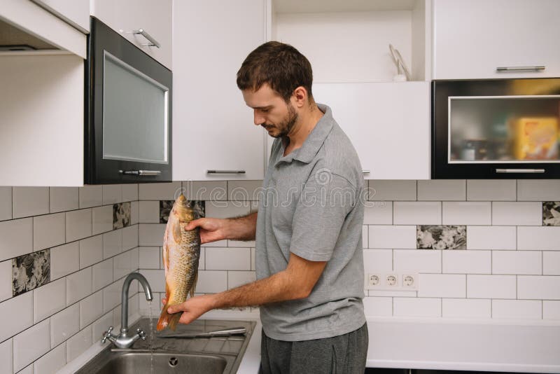 Man Cutting Fresh Fish in Kitchen in Home. Man Butchering Fish for Cook ...