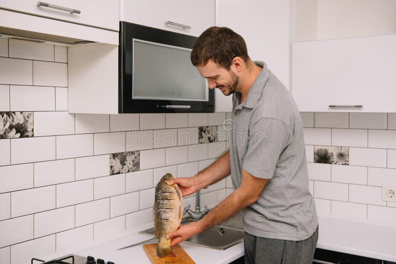 Man Cutting Fresh Fish in Kitchen in Home. Man Butchering Fish for Cook ...