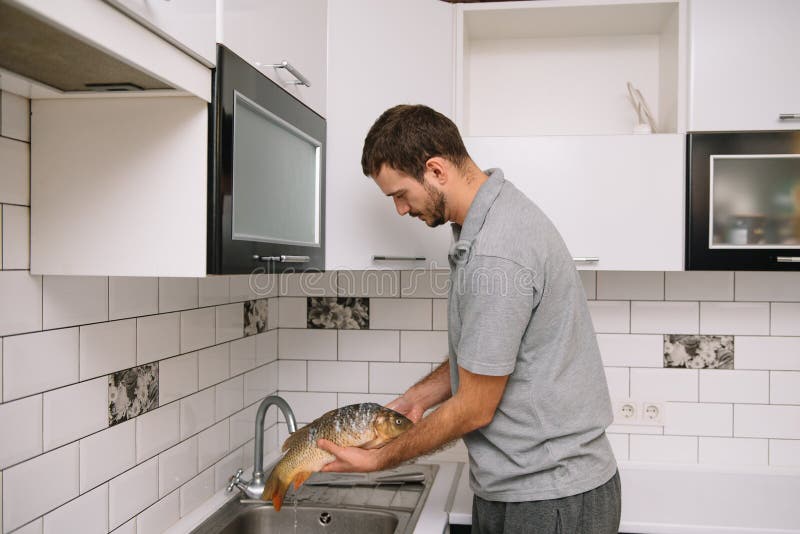 Man Cutting Fresh Fish in Kitchen in Home. Man Butchering Fish for Cook ...