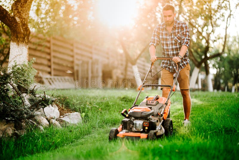 Man Cutting the Grass in Garden Using Lawn Mower and Professional ...