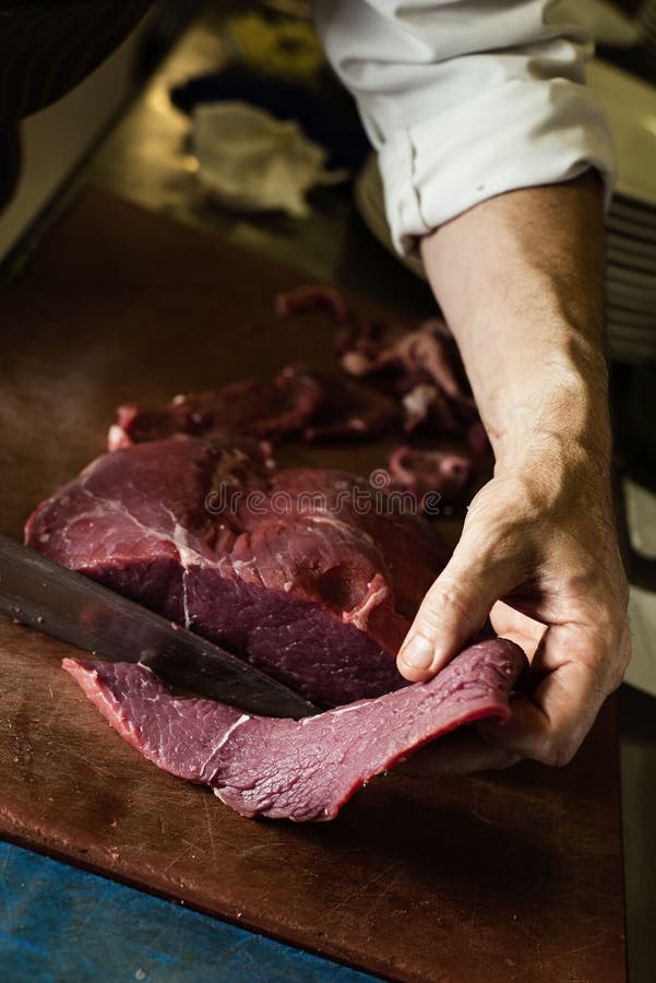 Man Cutting a Piece of Beef in a Professional Kitchen Stock Image ...