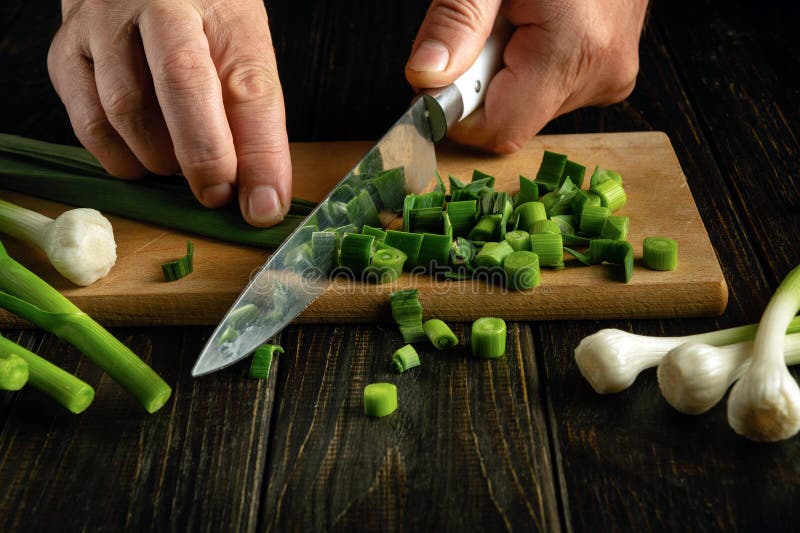 A Man Cutting Young Garlic with a Knife before Preparing a Vegetarian ...