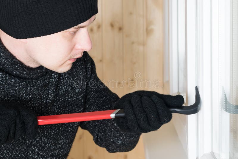 A Man in Dark Clothes Breaks a Plastic Window Using a Tool Stock Photo ...