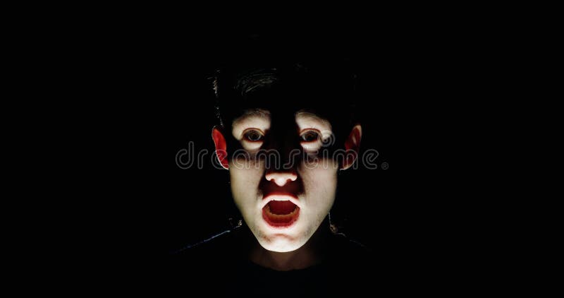 A Man in the Darkness, Dramatically Lit from Below, with an Open Mouth ...