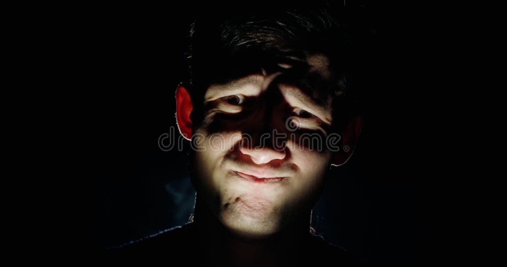 A Man in Darkness Makes a Bizarre and Unsettling Grimace, Illuminated ...
