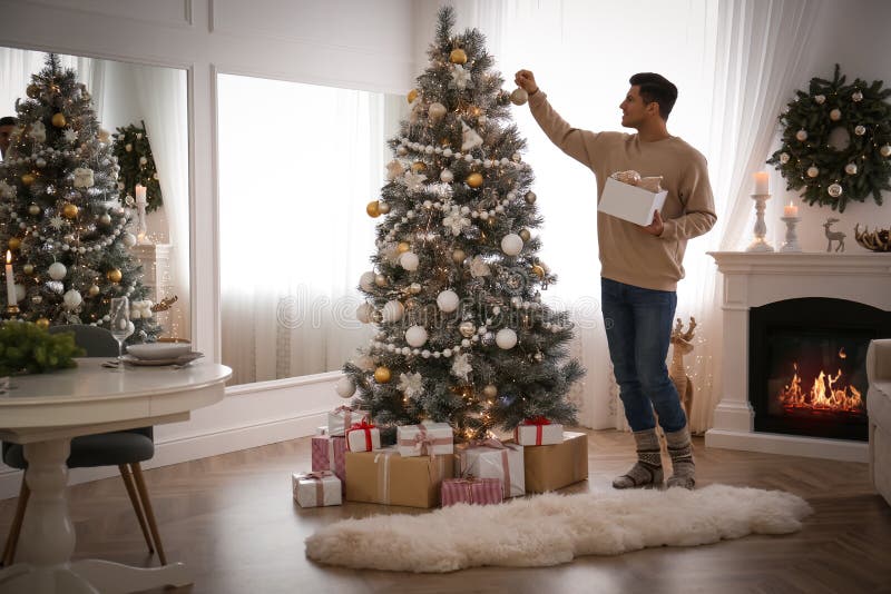 Man Decorating Christmas Tree in Beautiful Room Interior Stock Photo ...