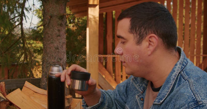 Man in a Denim Jacket Drinking from a Thermos Cup at a Construction ...