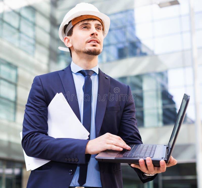 Man with Documents in Suit and Helmet Working at the Laptop Stock Photo ...