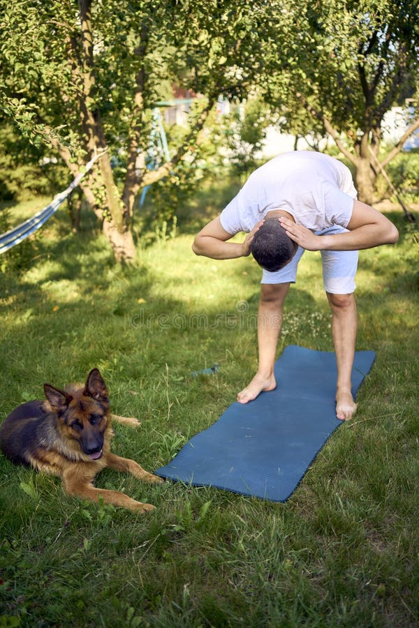 Man Does Somatic Exercises with His Dog in the Garden in the Morning ...
