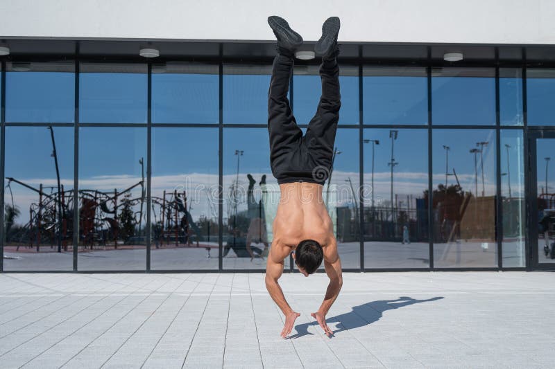 A Man Doing a Handstand Outdoors Against of Panoramic Windows. Stock ...