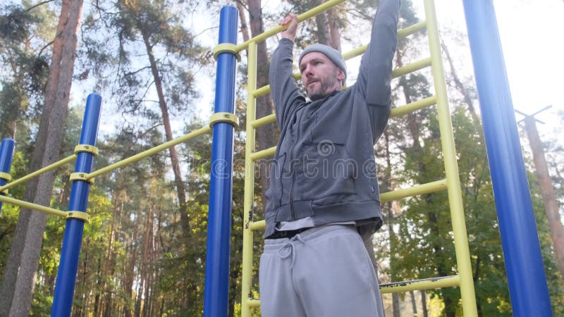 Man Doing Pull-ups on Outdoor Gym Equipment. Trees and Sky Background ...