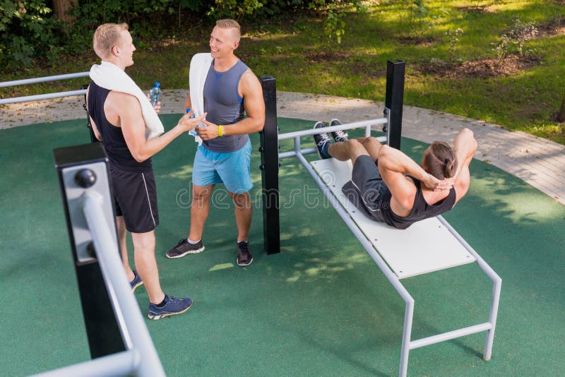 Man Doing Sit-ups and His Friends Resting Stock Photo - Image of ...