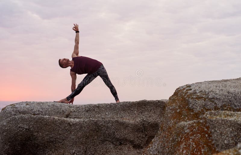 Man Doing the Triangle Pose on Some Rocks at Dusk Stock Photo - Image ...