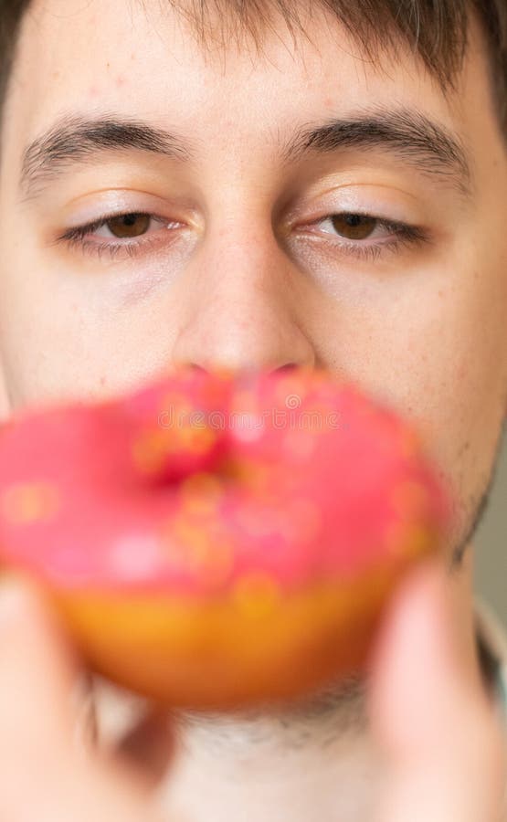 Man with Donut. Pink Bad Fat Doughnut in the Hands of a Man Stock Photo ...