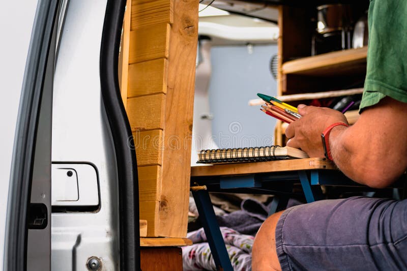 Man Drawing on a Notebook and Holding Pencils on a Table in a Converted ...
