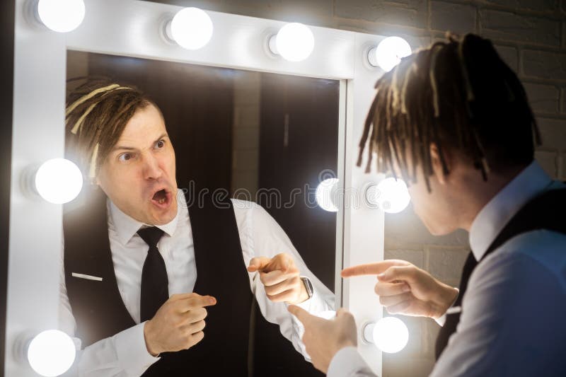 Man with Dreadlocks in Business Suit Grimacing, Looking in Mirror with ...