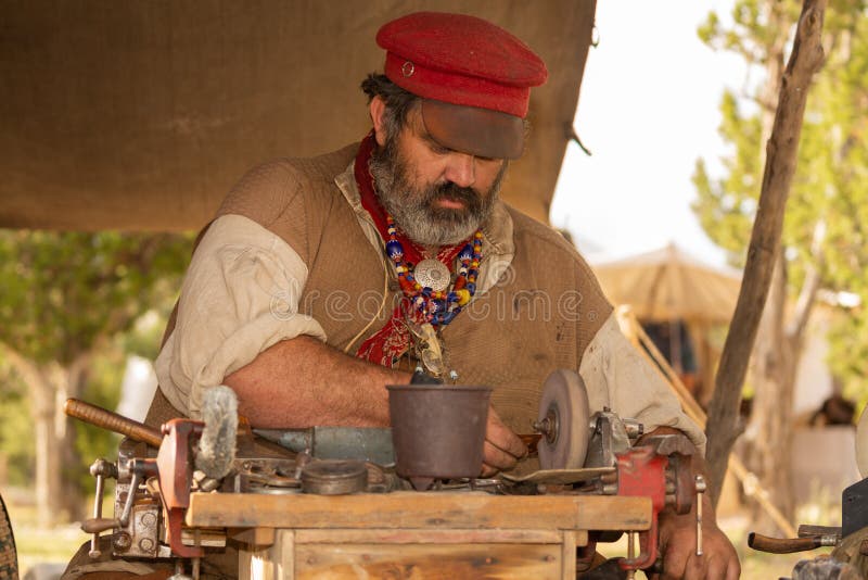 An 1800`s Tinker in a Mountain Man Festival Files the Edge of a Copper ...