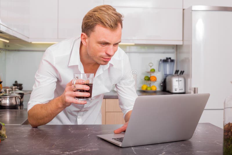 Man Drinking Coffee and Using Computer in Kitchen Stock Image - Image ...