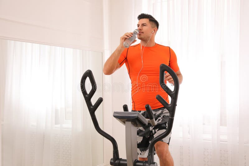 Man Drinking Water on Elliptical Machine at Home Stock Image - Image of ...