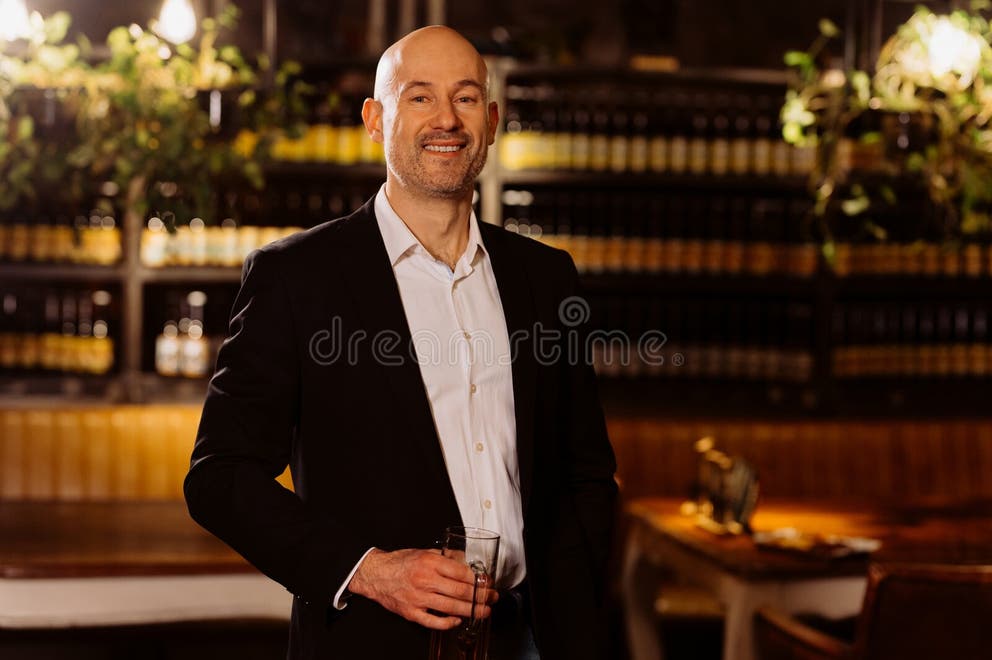 A Man Drinks Beer. Side View of Handsome Bald Man Drinking Beer in ...